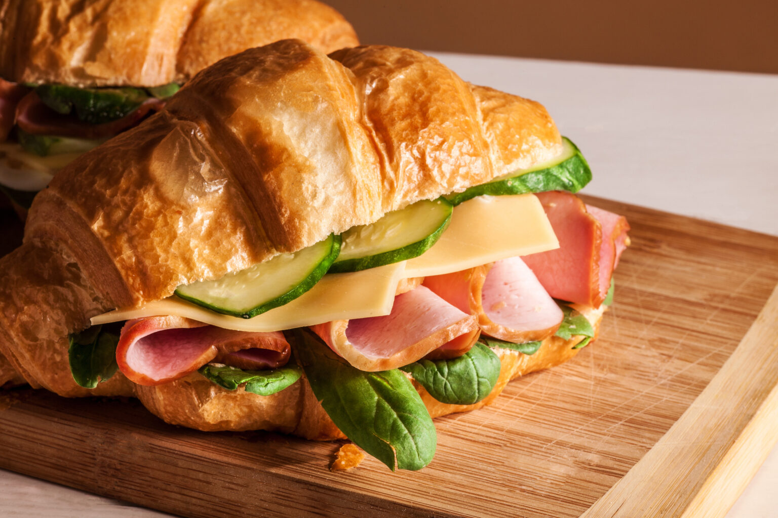 Croissant met ham, kaas, komkommer en basilicum
